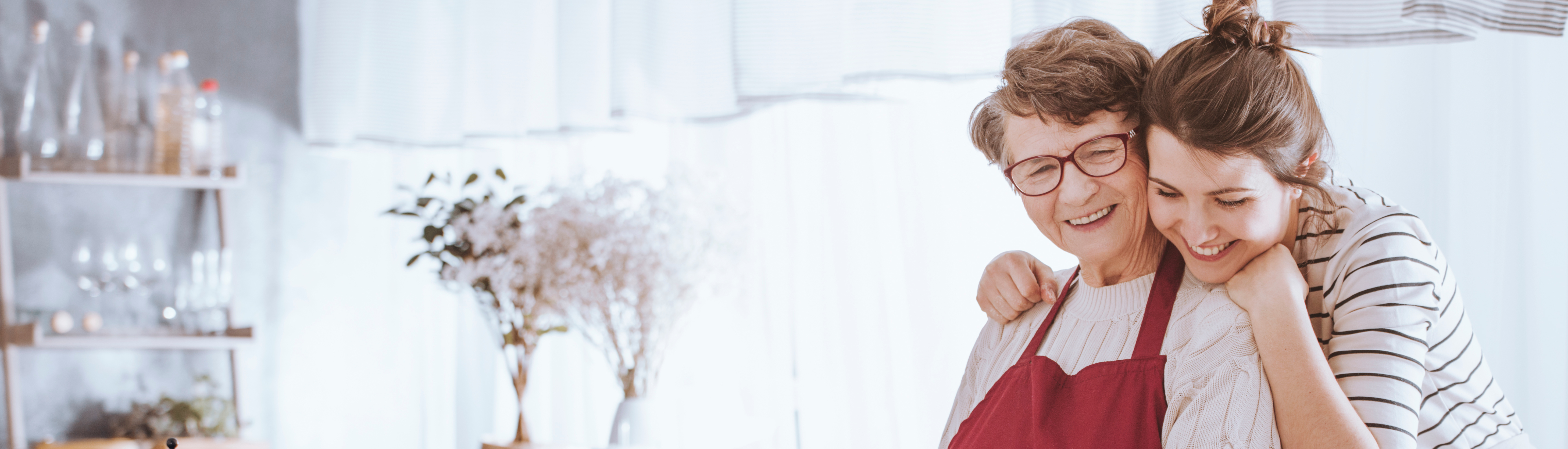 Grandmother-Receiving-Hug-From-Granddaughter-in-Kitchen - Care N' Care